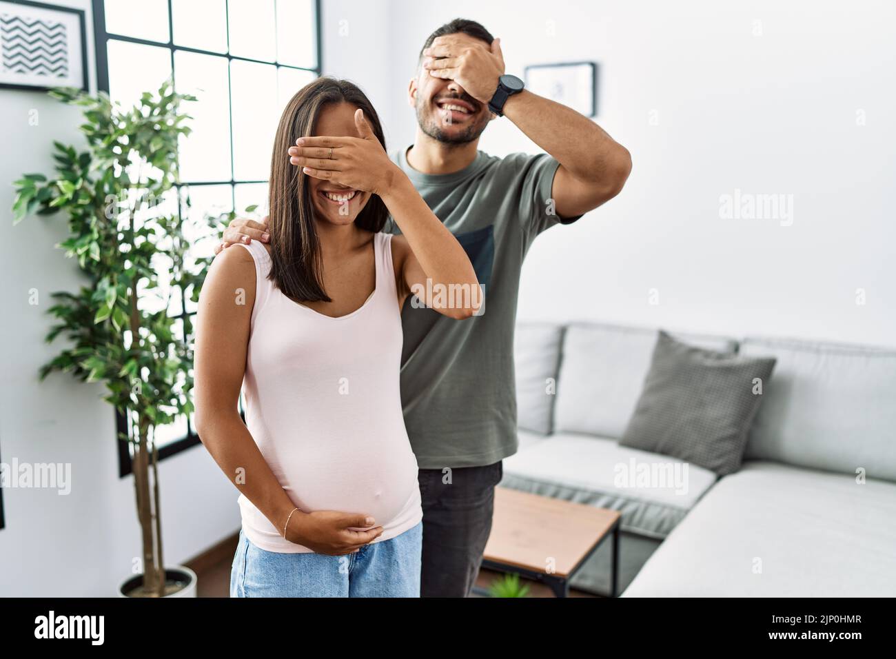 Young interracial couple expecting a baby, touching pregnant belly ...