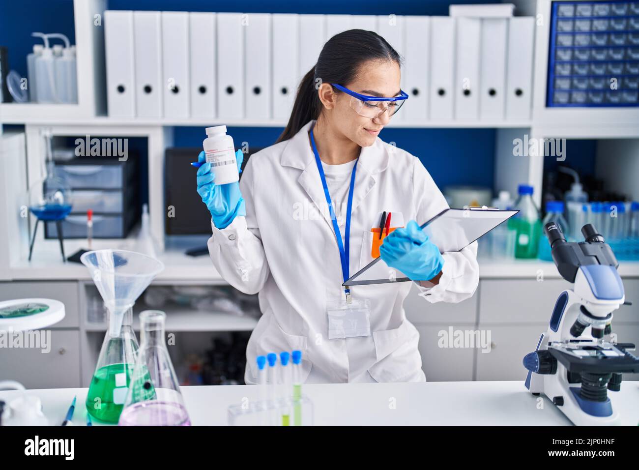 Young hispanic woman scientist holding pills at laboratory Stock Photo ...