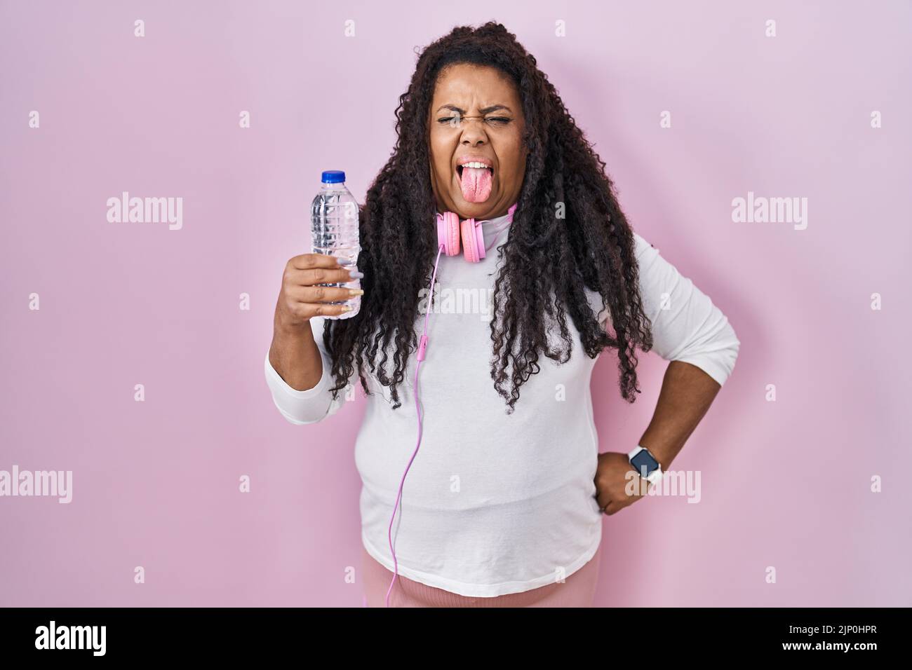 Plus size hispanic woman wearing sportswear and headphones sticking ...