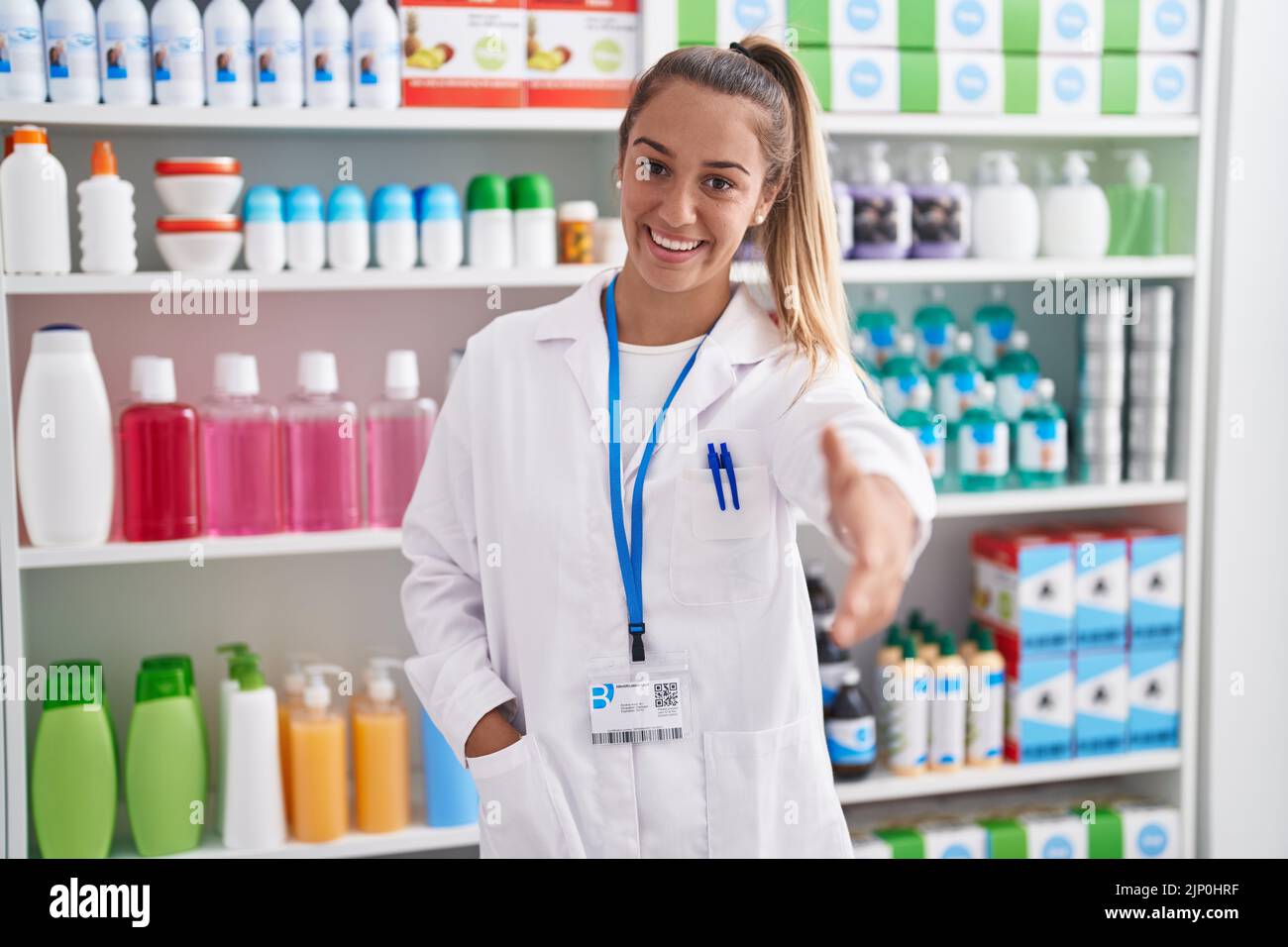 Young beautiful hispanic woman pharmacist smiling confident shake hand ...