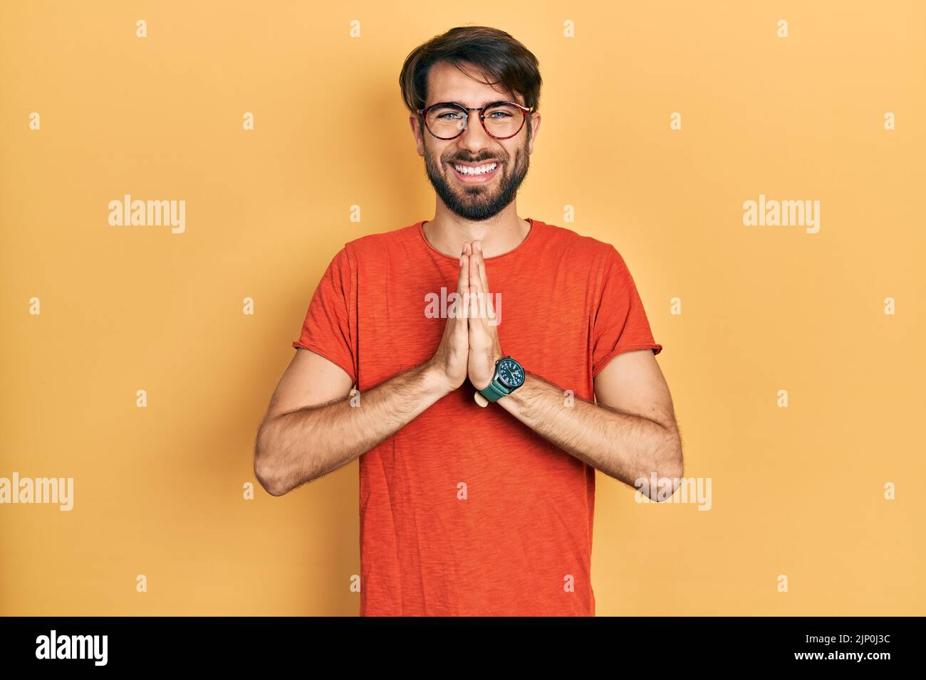 Young hispanic man wearing casual clothes and glasses praying with ...