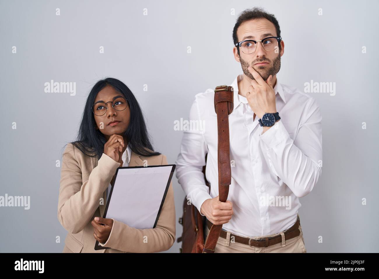 Interracial business couple wearing glasses with hand on chin thinking ...