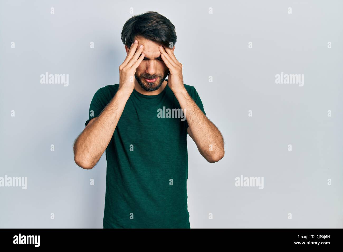 Young hispanic man wearing casual white tshirt with hand on head for ...