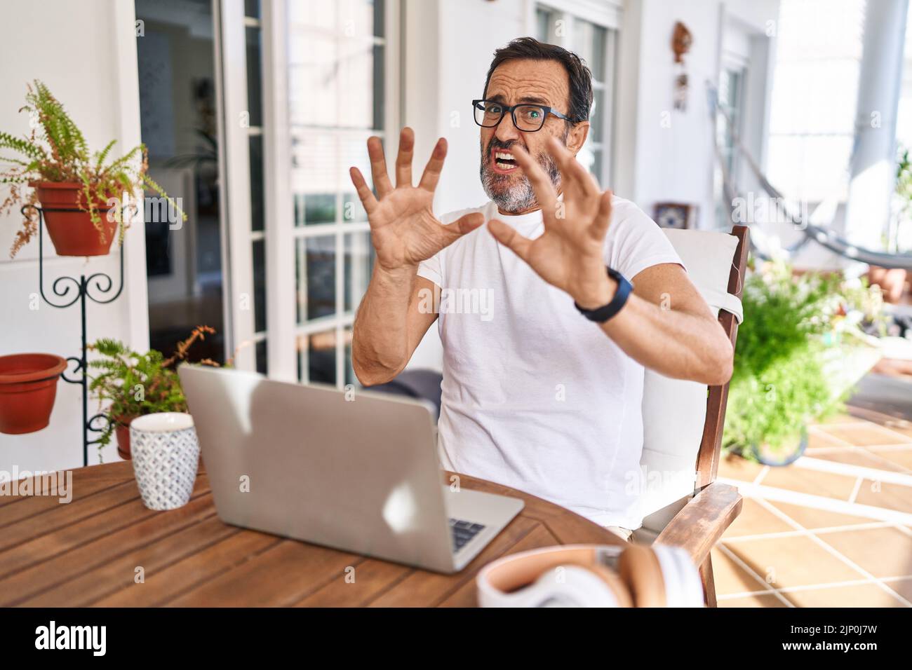 Middle age man using computer laptop at home afraid and terrified with ...