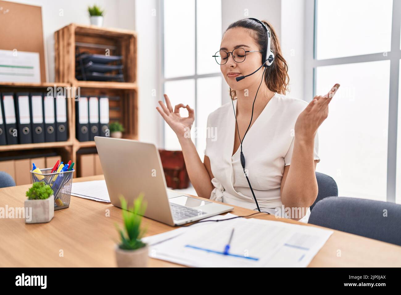 Young hispanic woman wearing call center agent headset at the office ...