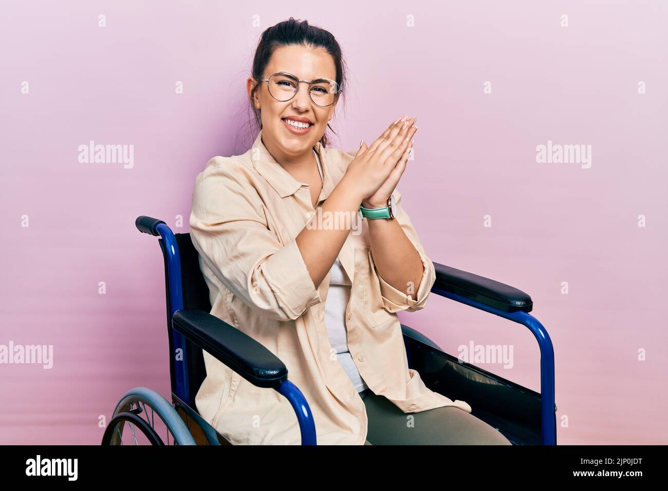 Young hispanic woman sitting on wheelchair clapping and applauding ...