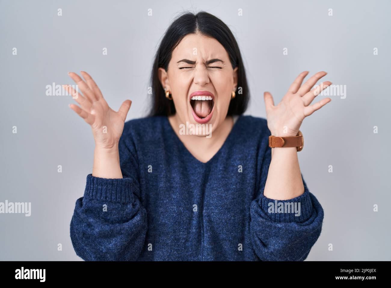 Young brunette woman standing over isolated background celebrating mad ...