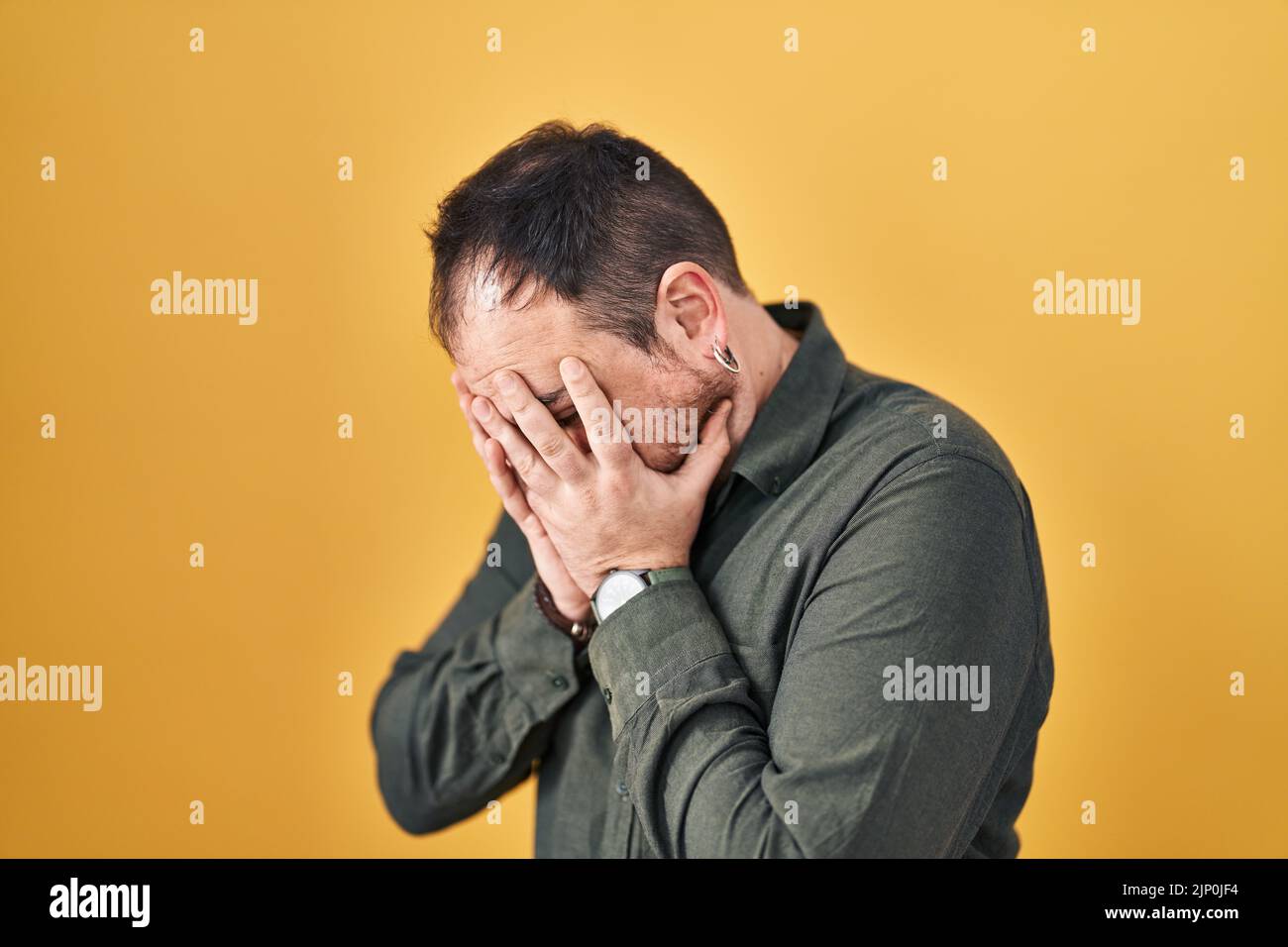 Plus size hispanic man with beard standing over yellow background with ...