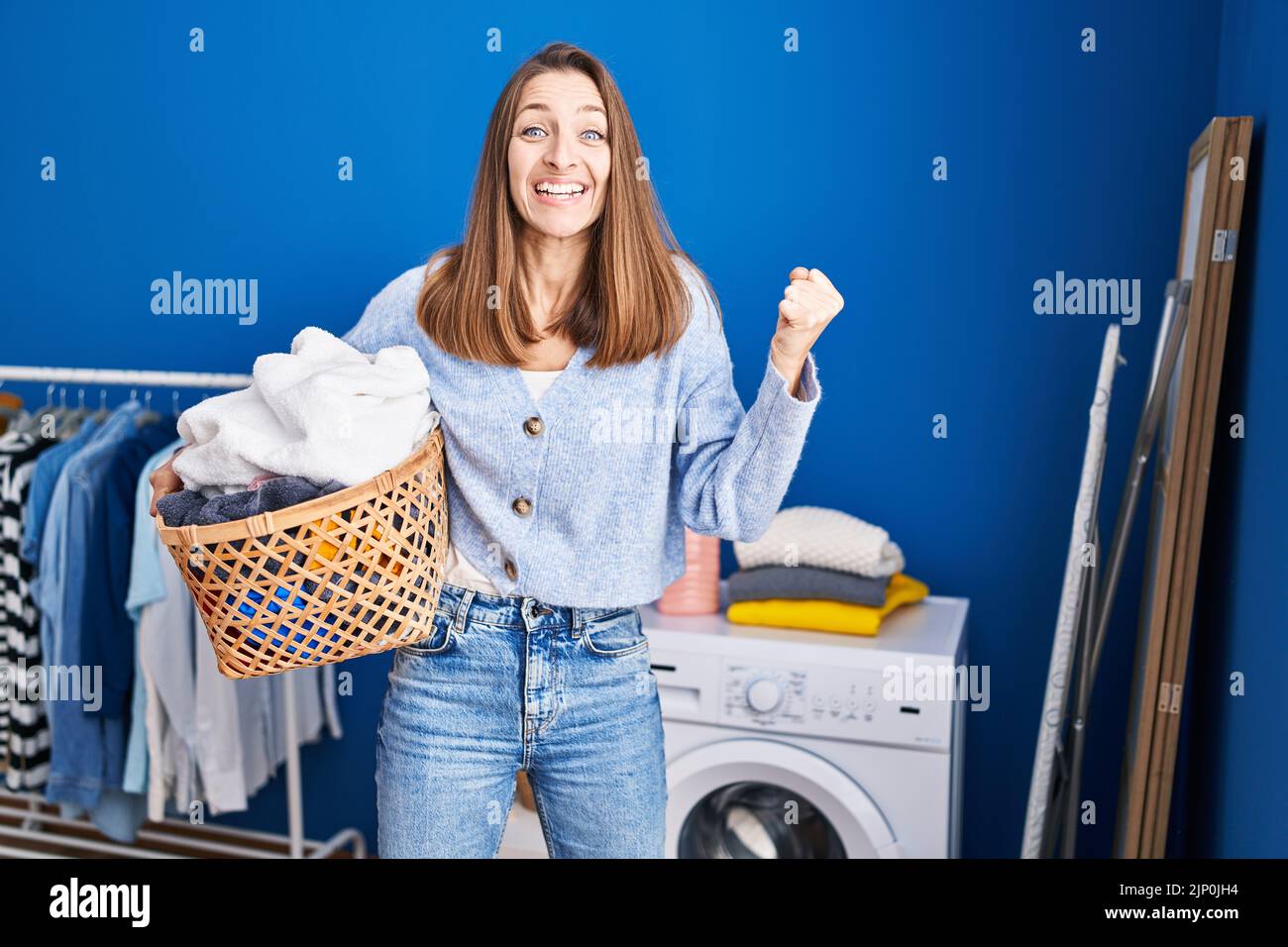 Young woman holding laundry basket screaming proud, celebrating victory ...