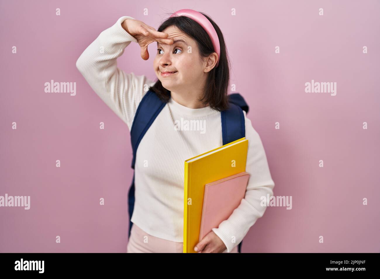 Woman with down syndrome wearing student backpack and holding books ...