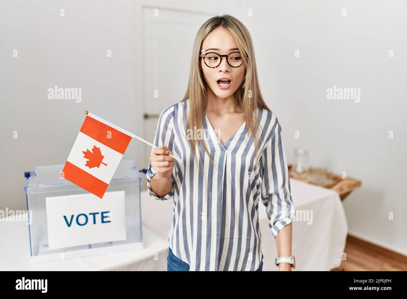 Asian young woman at political campaign election holding canada flag ...