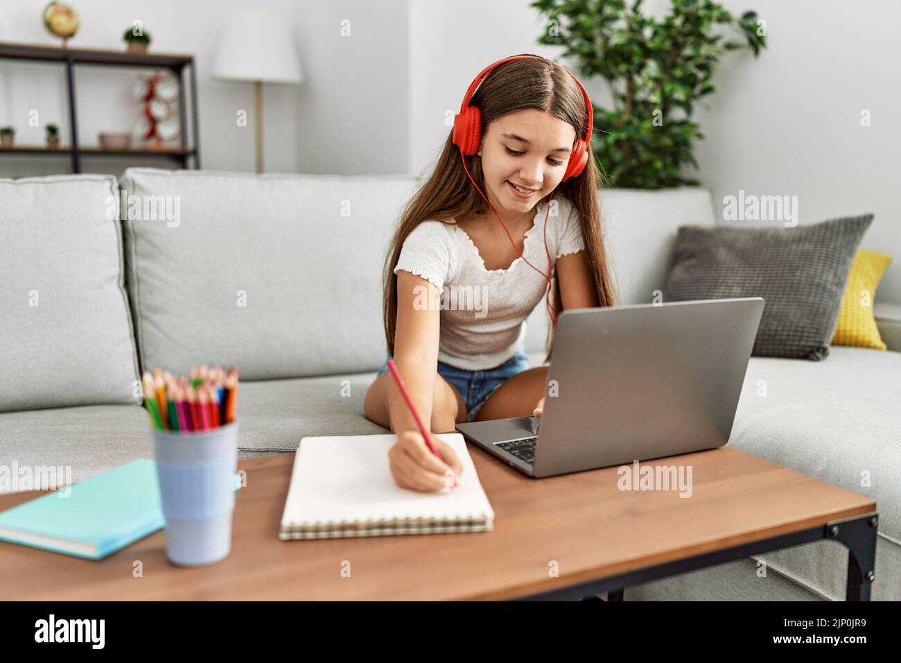 Adorable girl doing homework using laptop at home Stock Photo - Alamy