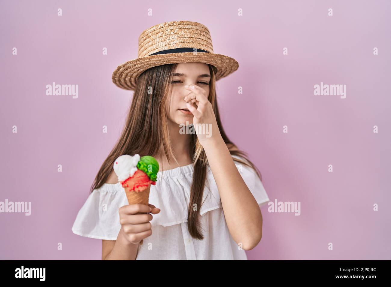 Teenager girl holding ice cream smelling something stinky and ...