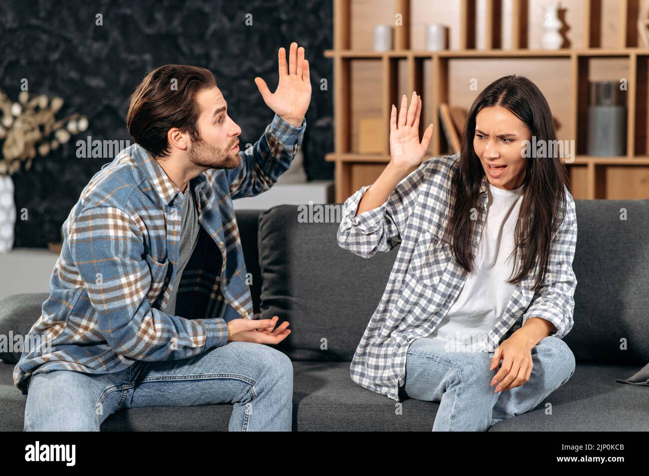Caucasian couple sitting on sofa in living room, quarreling over ...