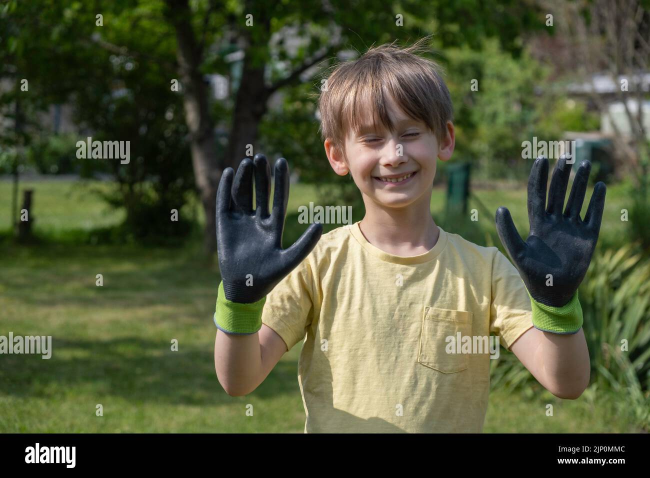 Boy in home garden wearing gardening gloves Stock Photo - Alamy