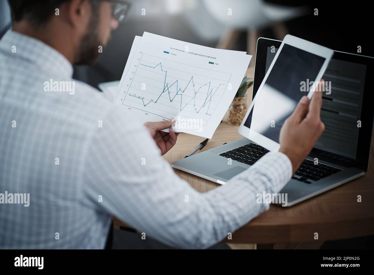 Reviewing business trends to help make better improvements. a young businessman using a digital ...