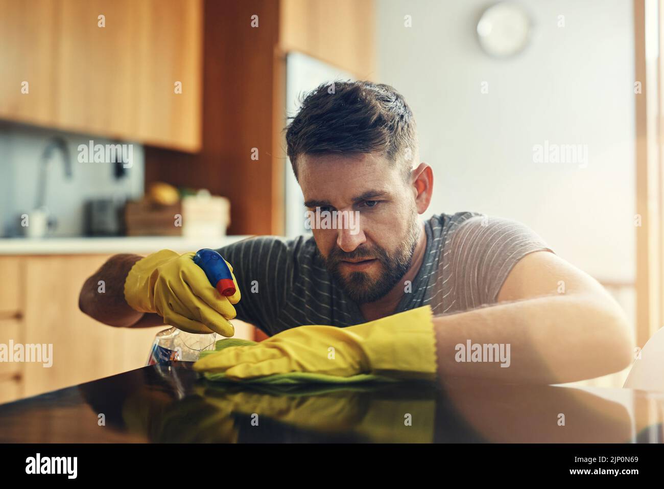 No germs under my watch. a young man cleaning the kitchen counter at ...