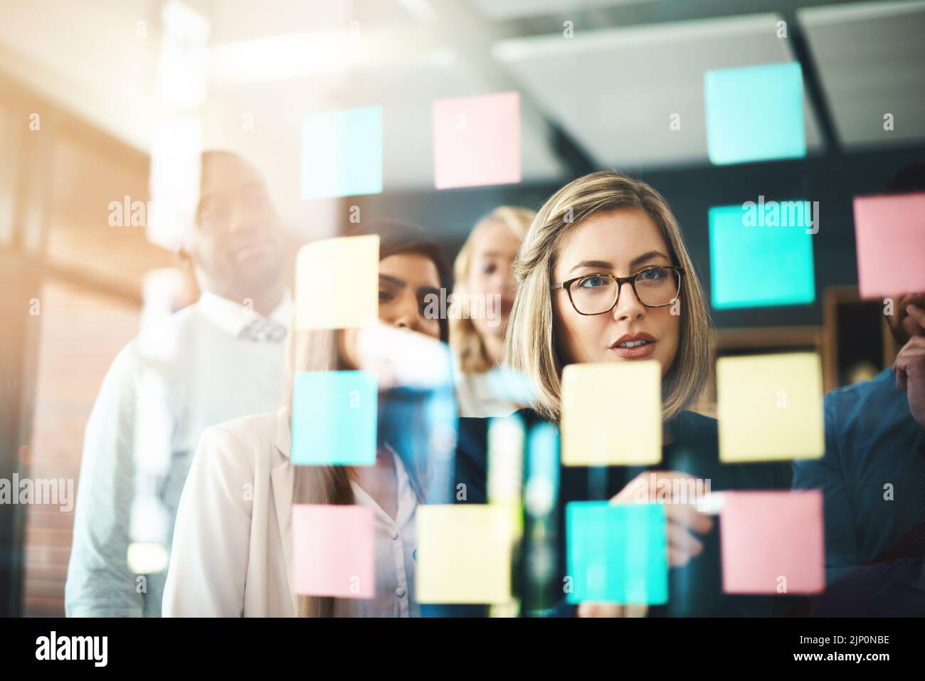 Team leader planning ideas and writing on sticky notes while talking ...