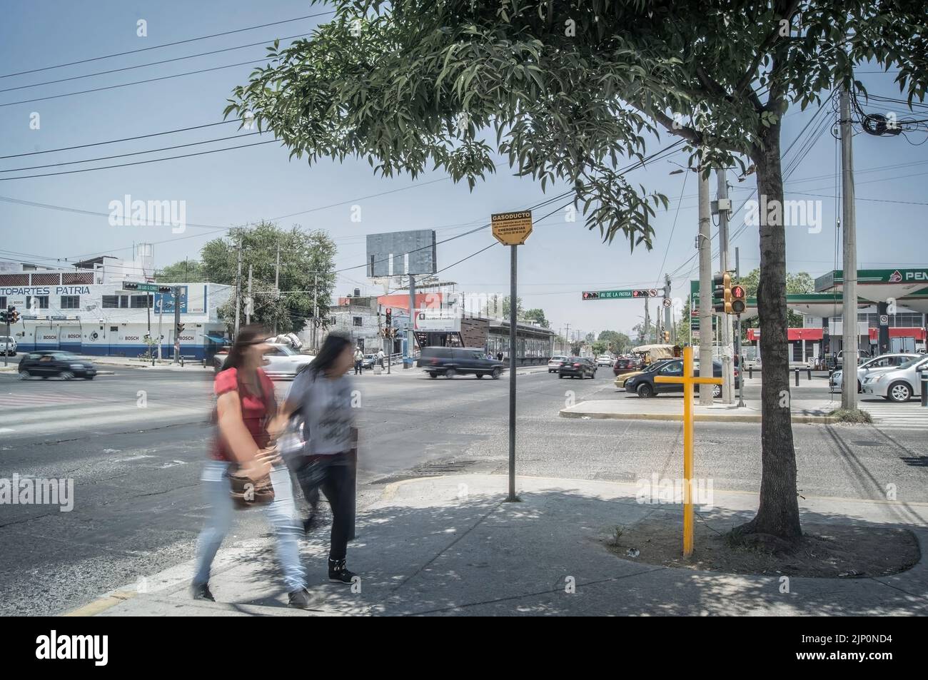 two people crossing the street with a yellow cross, in the background ...