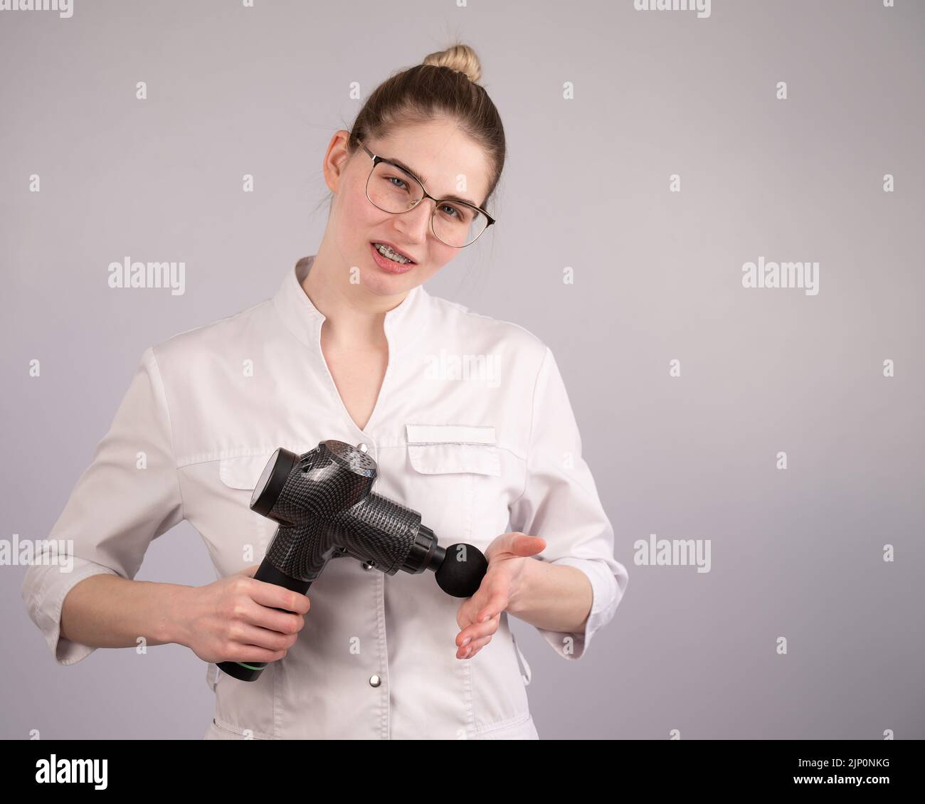 The masseur doctor holds a masseur gun on a white background Stock ...