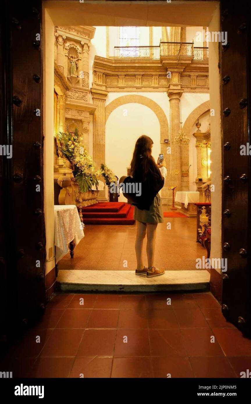 woman standing at the side entrance of a church, taking a picture with ...