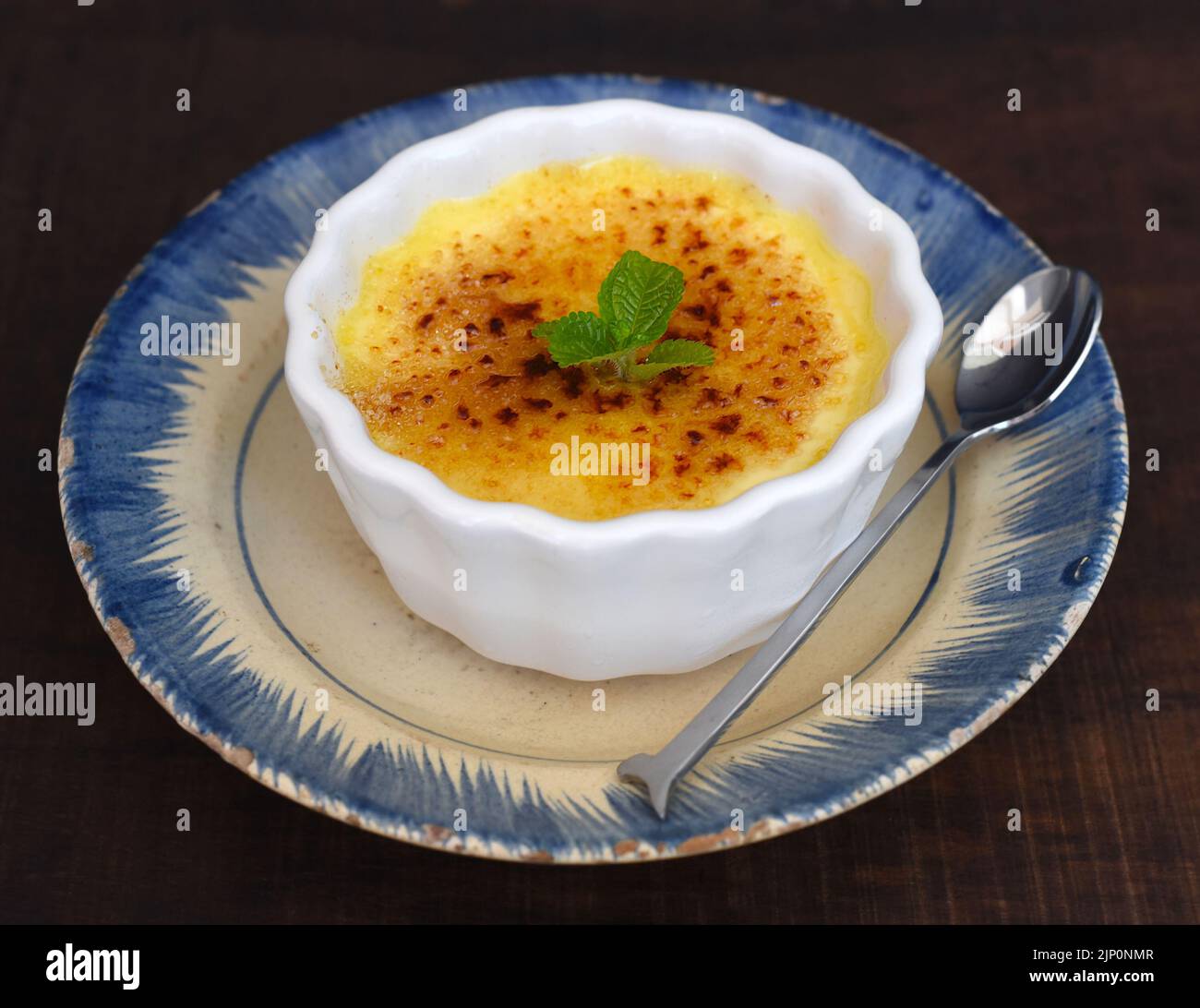 Creme brulee in a ceramic bowl on wooden table and black background ...