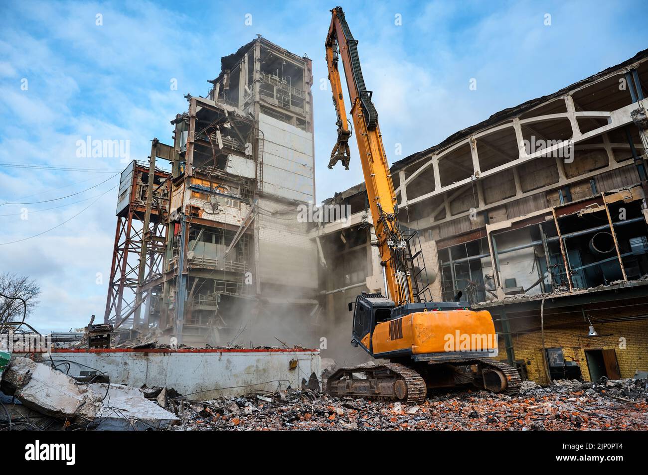 Disassembling of old industrial building by high excavator Stock Photo - Alamy