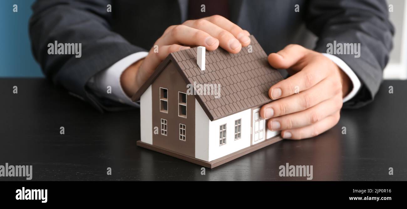 Real estate agent with model of house at table, closeup Stock Photo - Alamy