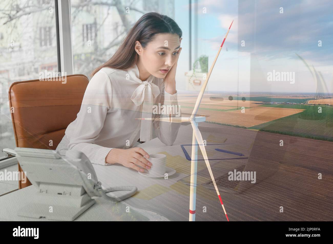 Double exposure of businesswoman using laptop in office and windmill ...