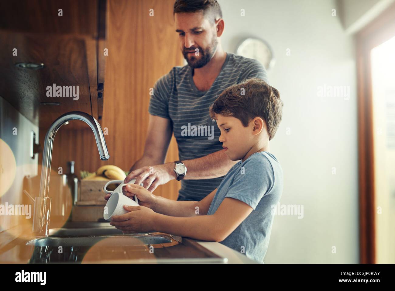 First we eat together then we clean together. a father and son washing ...