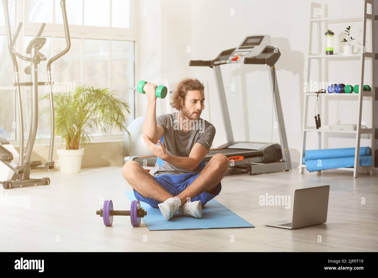 Sporty young man with laptop training in gym Stock Photo - Alamy