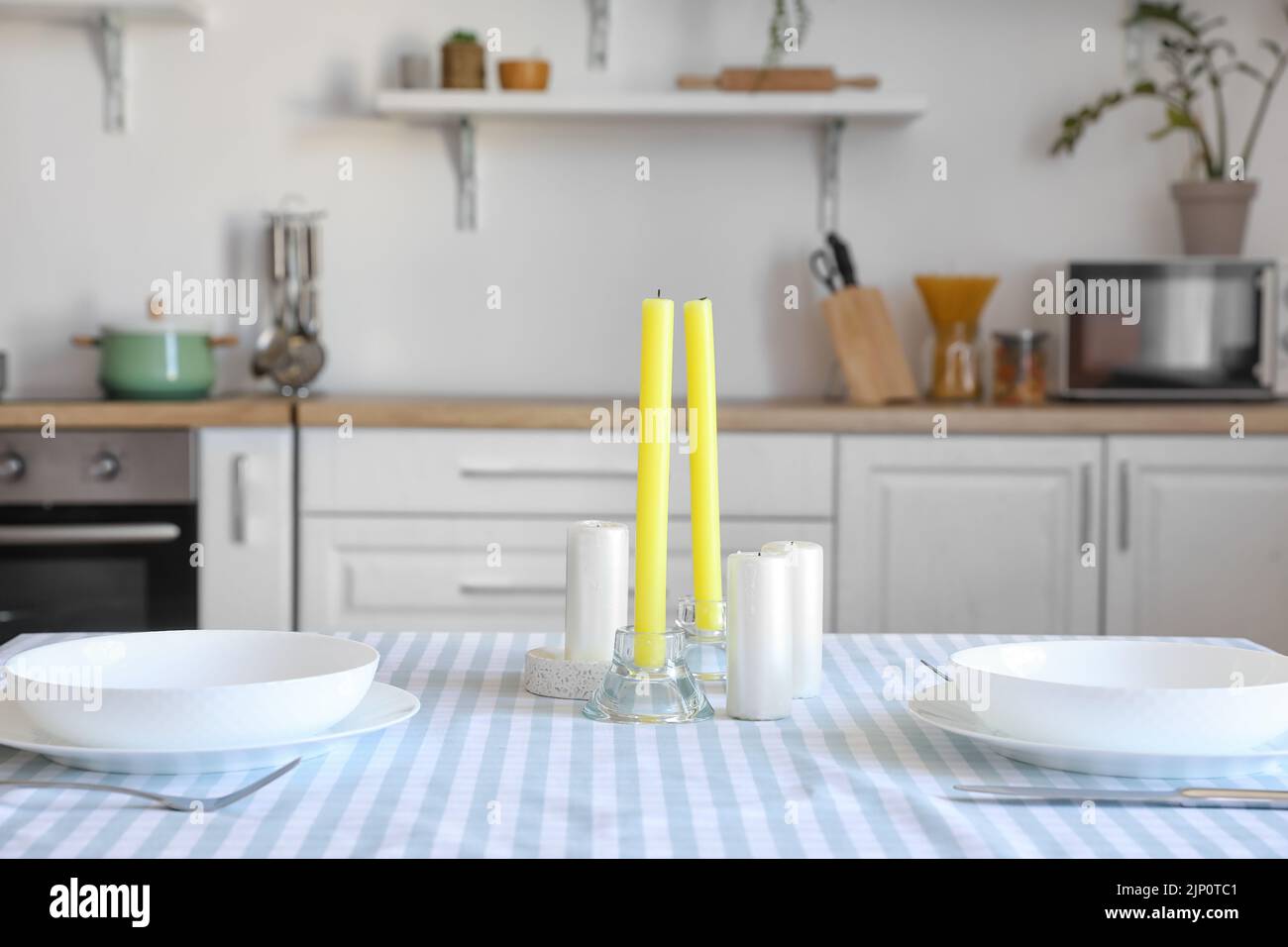 Simple table setting with candles in kitchen Stock Photo - Alamy