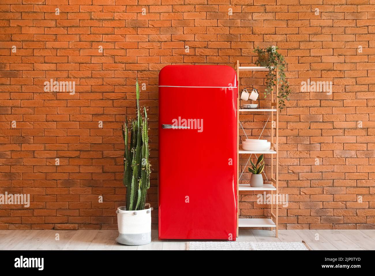 Red fridge, shelving unit with dishes and houseplants near brick wall ...