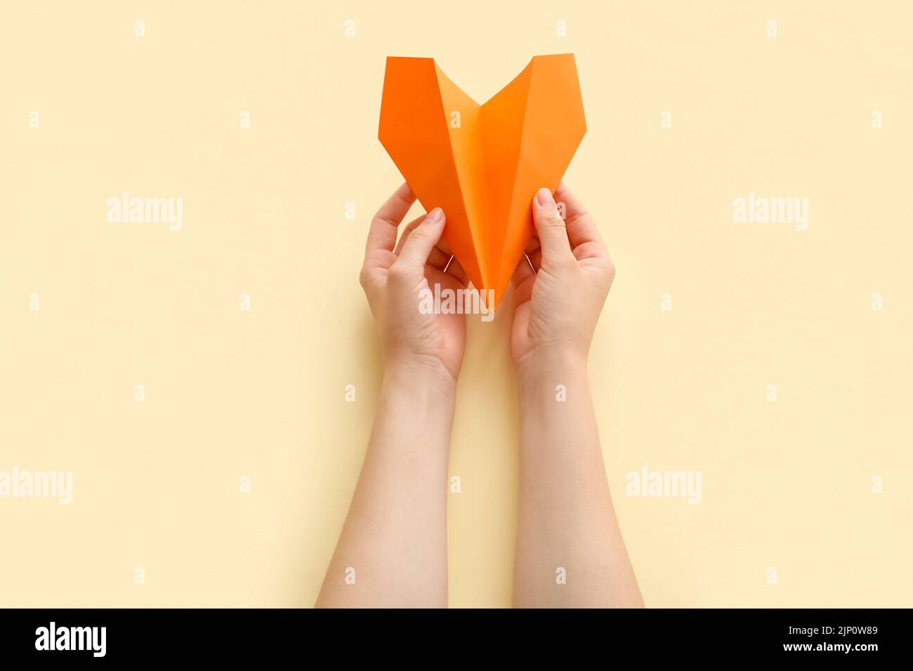 Woman with orange paper plane on beige background Stock Photo - Alamy