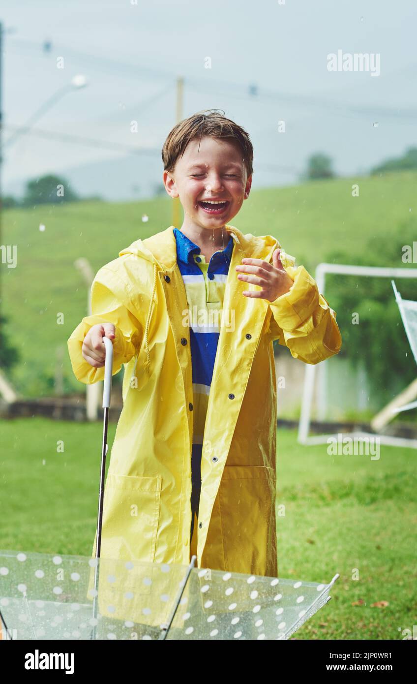 The rain doesnt bother him. a cheerful little boy standing with an ...