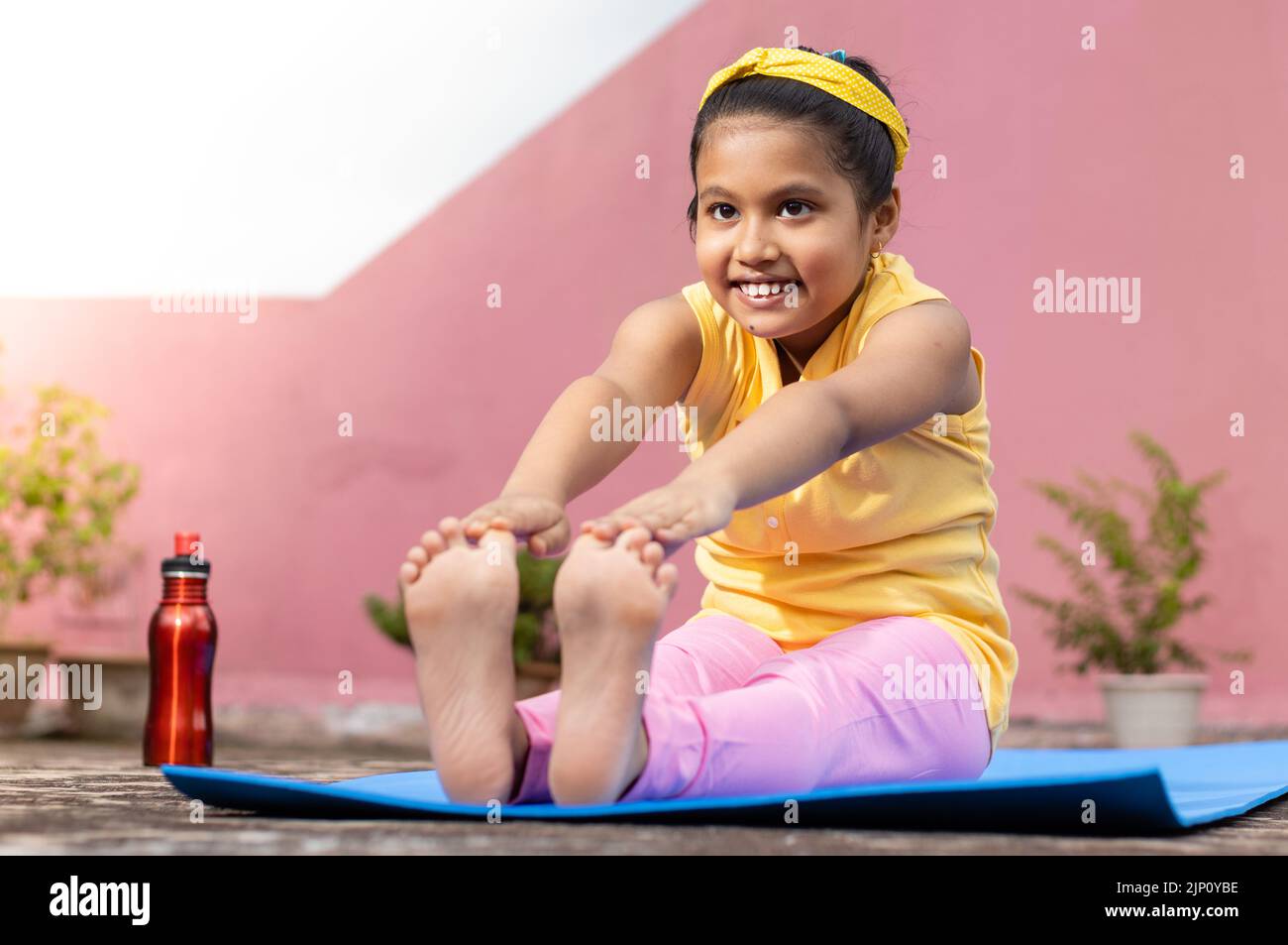 An Indian girl child practicing yoga in smiling face on yoga mat ...