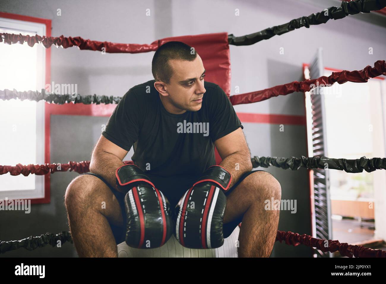 Taking a breather. a confident young male boxer seated in the corner of ...