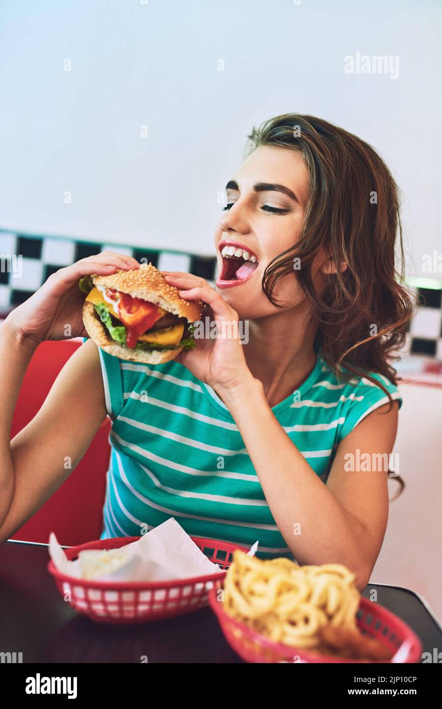 Now thats a mouthful. an attractive young woman enjoying a burger in a ...