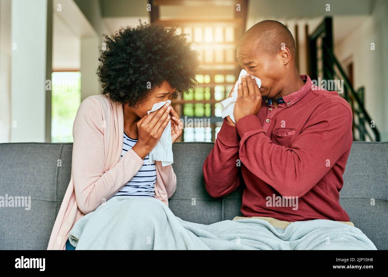 We made each other sick. a young couple blowing their noses at home ...