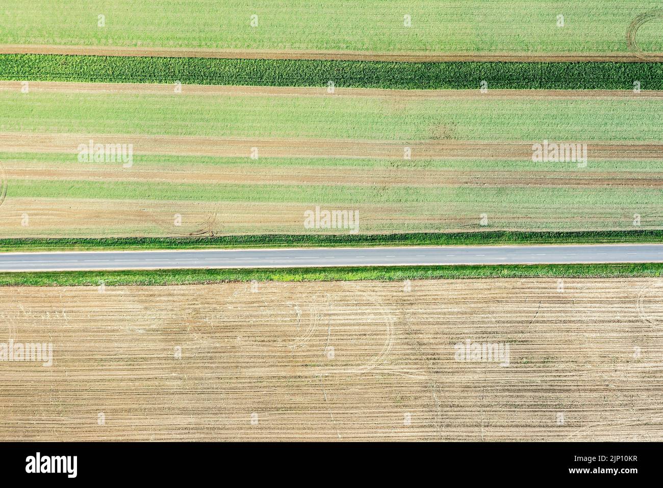 empty country road between agricultural plowed fields. aerial top drone ...