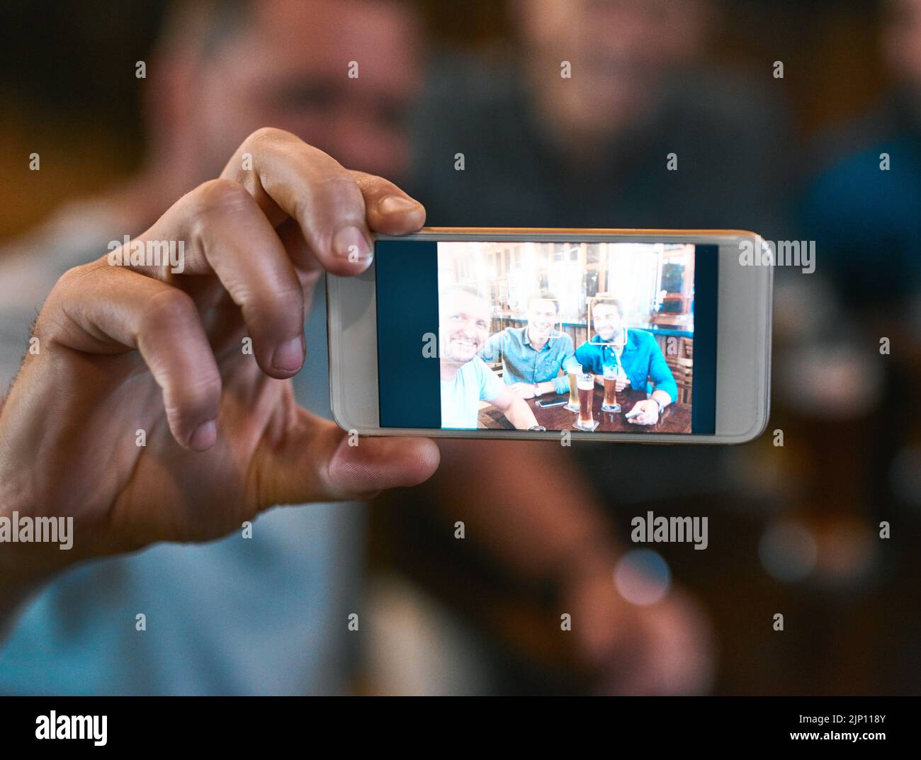 Fit in for the picture guys. three young men drinking beer at a table ...