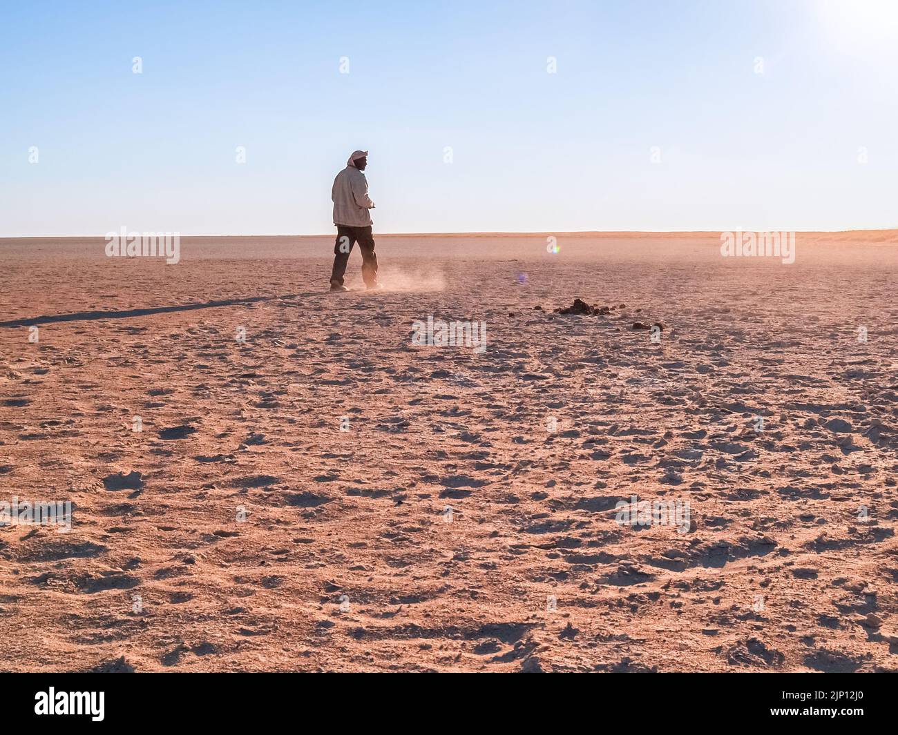 Botswana Africa - August 29 2007; Man walking across desert kicking up ...