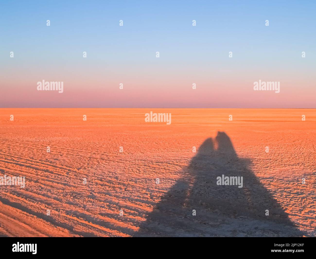 Long red desert shadow of quad-bike and rider touring at sunset ...