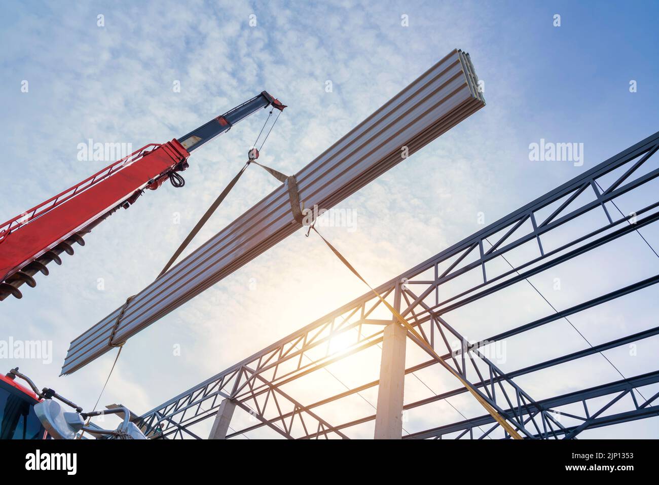 A crane is lifting the PU foam roof sheet on the steel roof structure ...