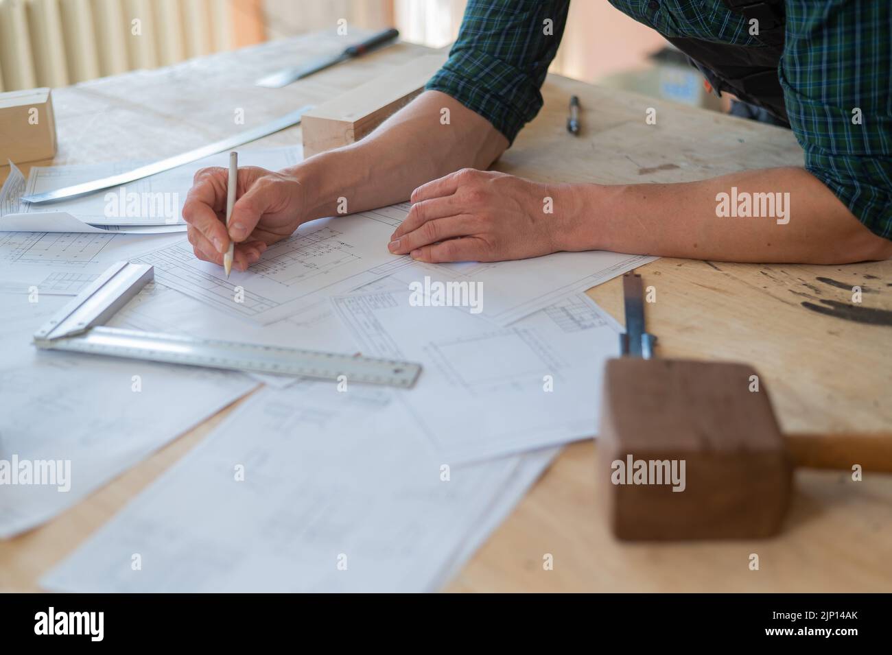 A portrait of a carpenter in goggles and work overalls draws a ...