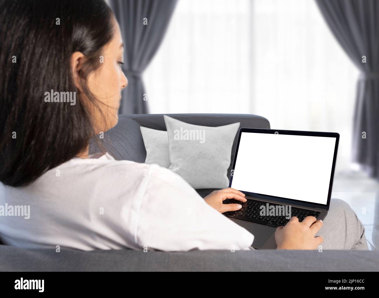 Holding laptop, young caucasian woman relaxing on sofa holding laptop ...
