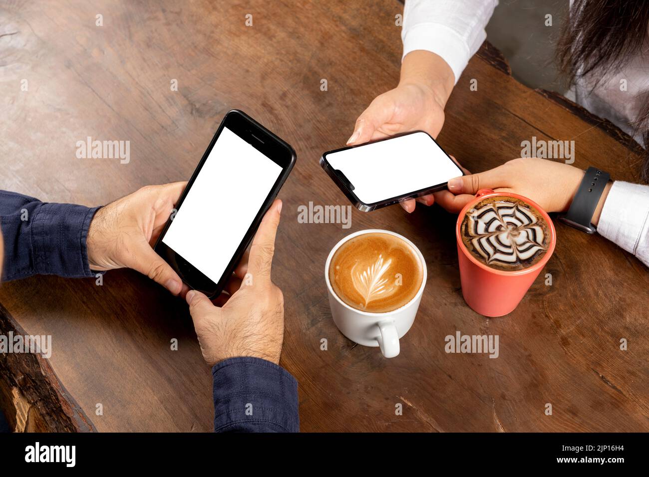 Two smartphone mock up, couple sitting on the wooden table and holding ...