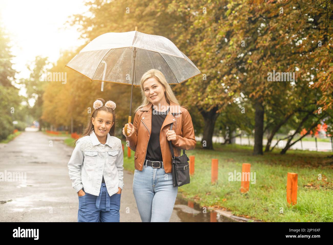 Mom holds a transparent umbrella from which fall autumn leaves ...
