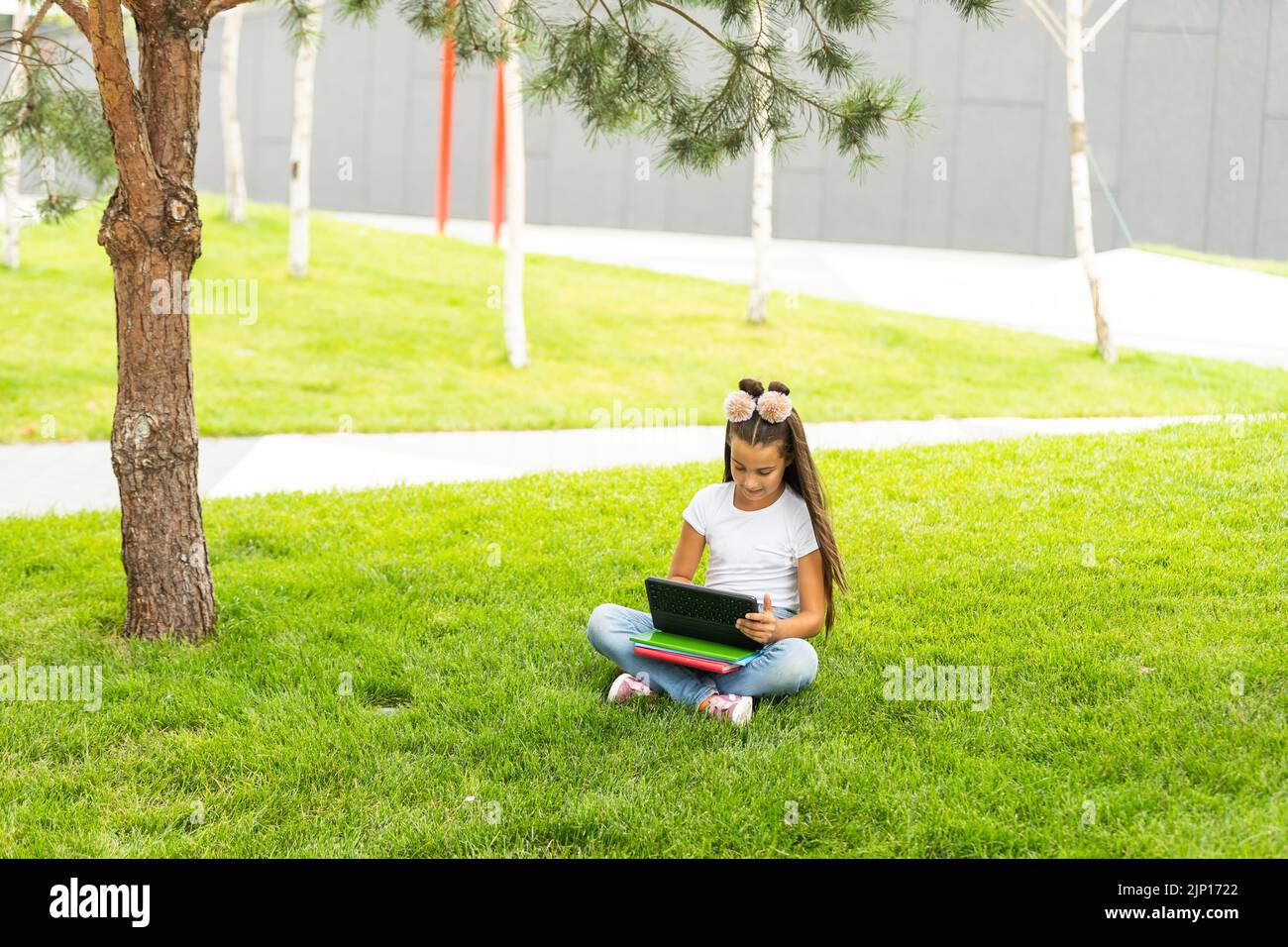 Little girl sitting on grass and playing tablet pc Stock Photo - Alamy
