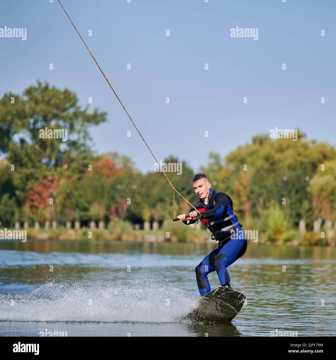 Wakeboarder surfing on lake. Young man surfer having fun wakeboarding ...
